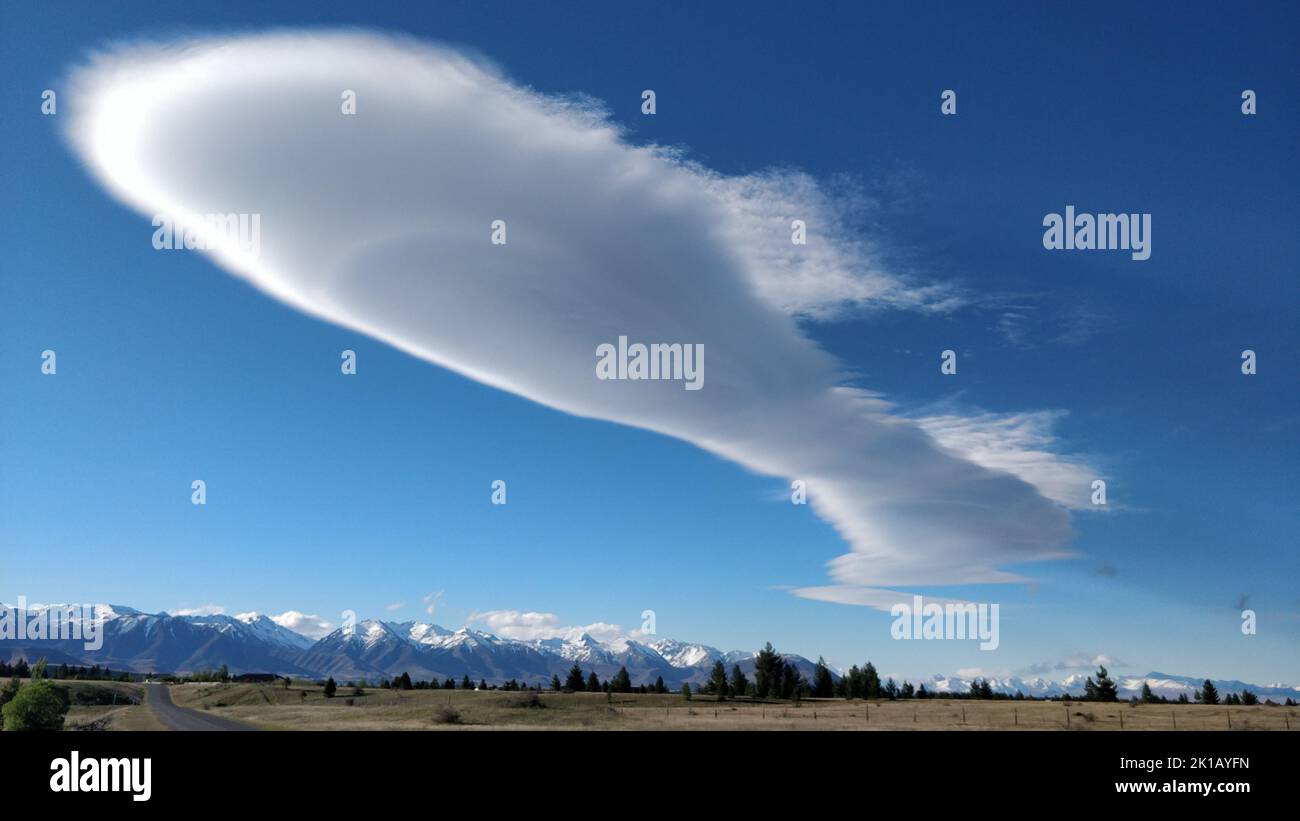 An interesting shaped huge cloud in the clear sky against a countryside ...