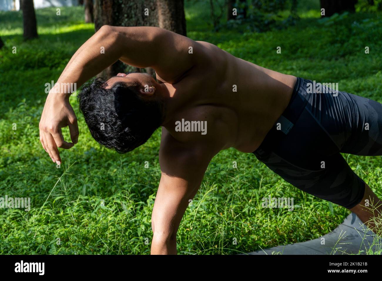 The vertical view of a Hispanic man doing a yoga spine flexibility pose ...