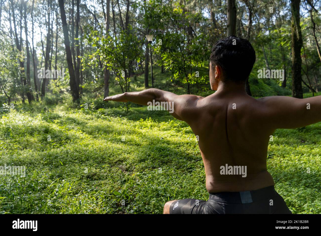 The view of a Hispanic man doing the virabhadrasana II yoga pose from ...