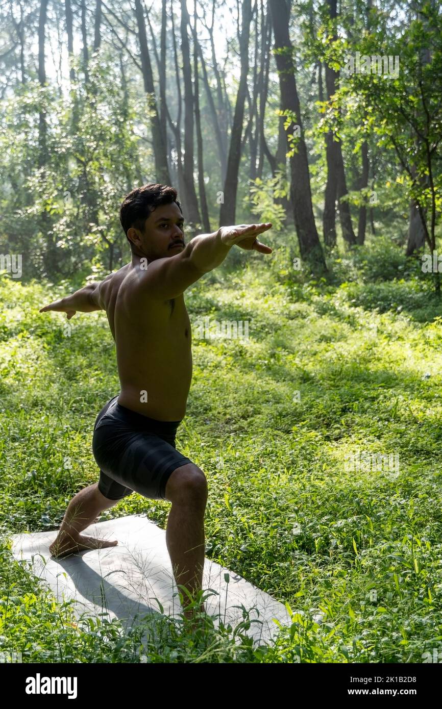 The vertical view of a Hispanic man doing the virabhadrasana II yoga ...
