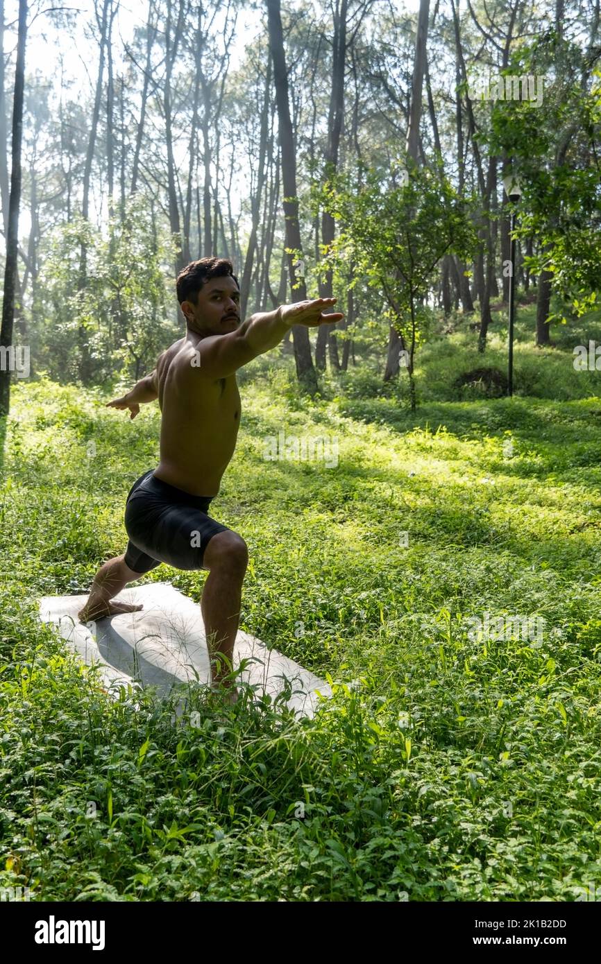 The vertical view of a Hispanic man doing the virabhadrasana II yoga ...