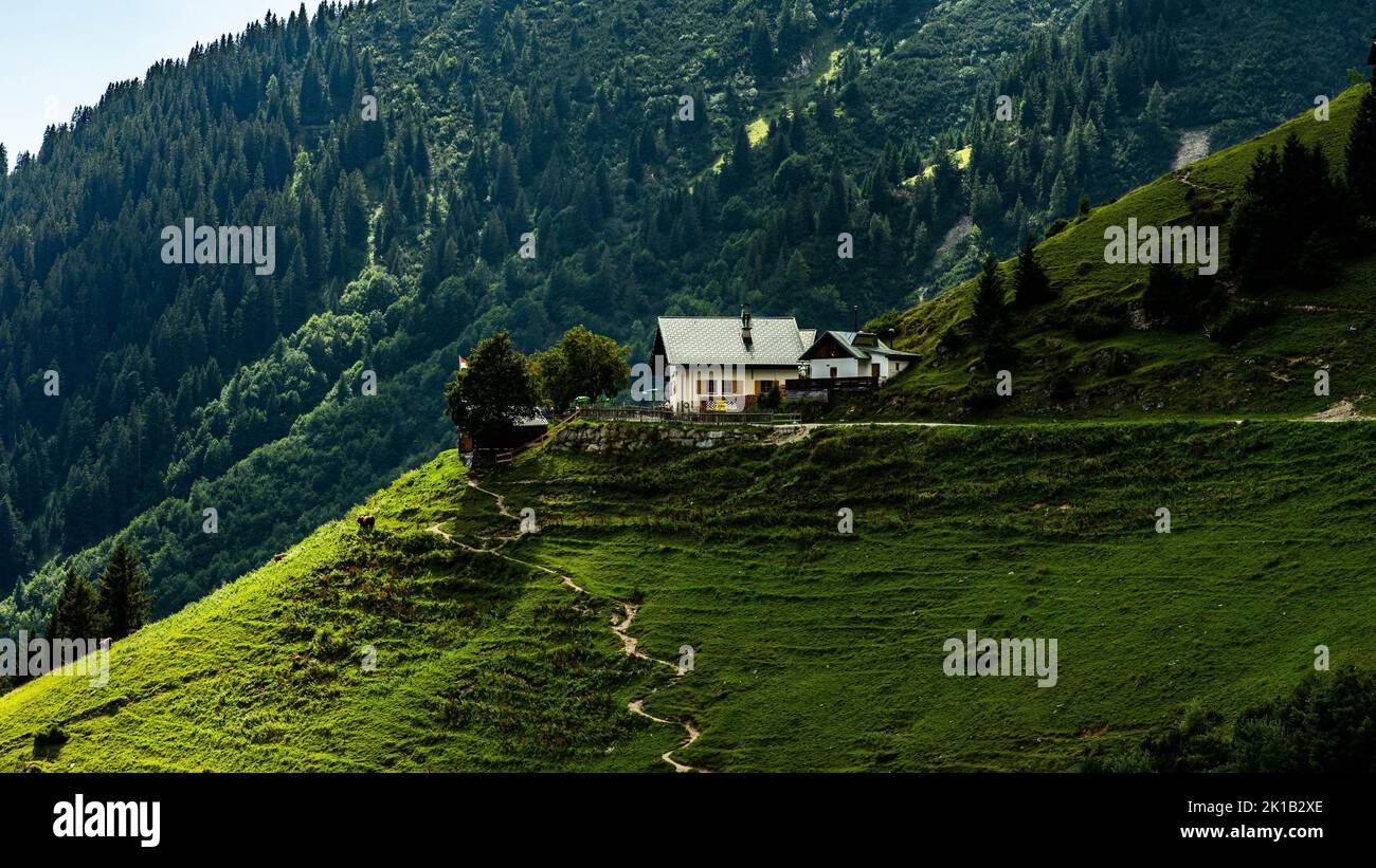 A tranquil scenery of a small house on the green slope of a mountain ...