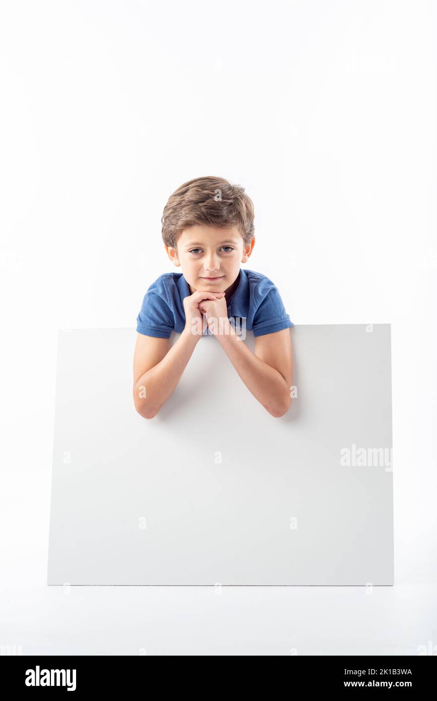 Funny Caucasian boy showing a white advertising poster with space for ...