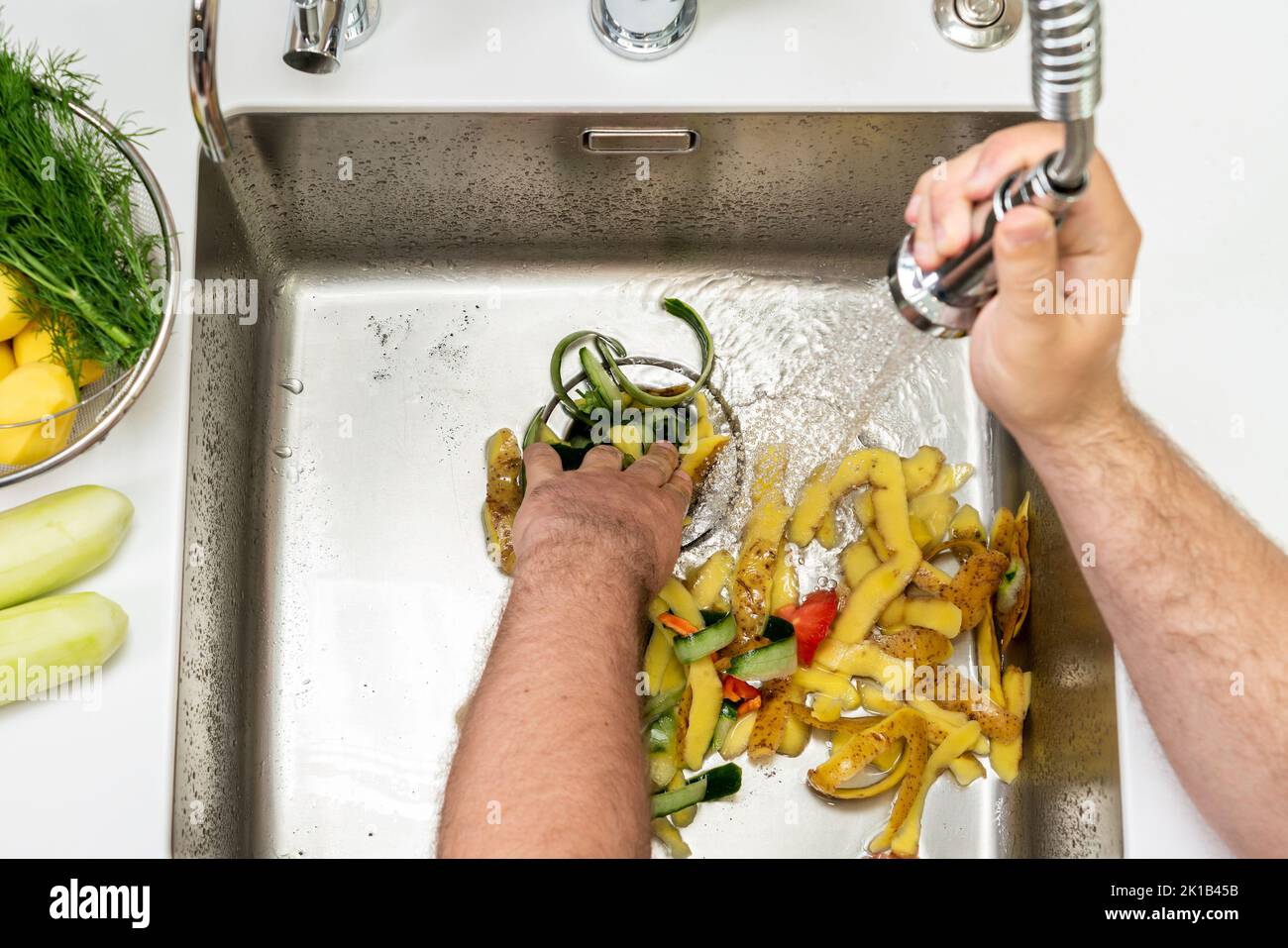 Food waste in the dispenser hole in the kitchen sink and a jet of water ...