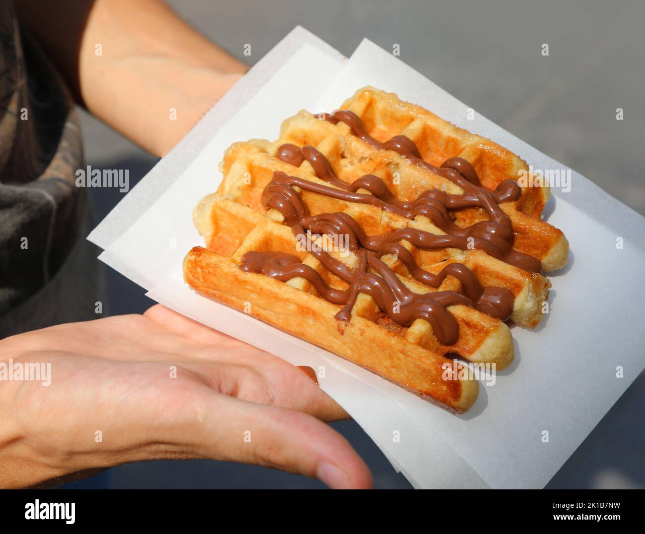 waffle typical Belgian dessert with hazelnut cream garnish on the hands ...