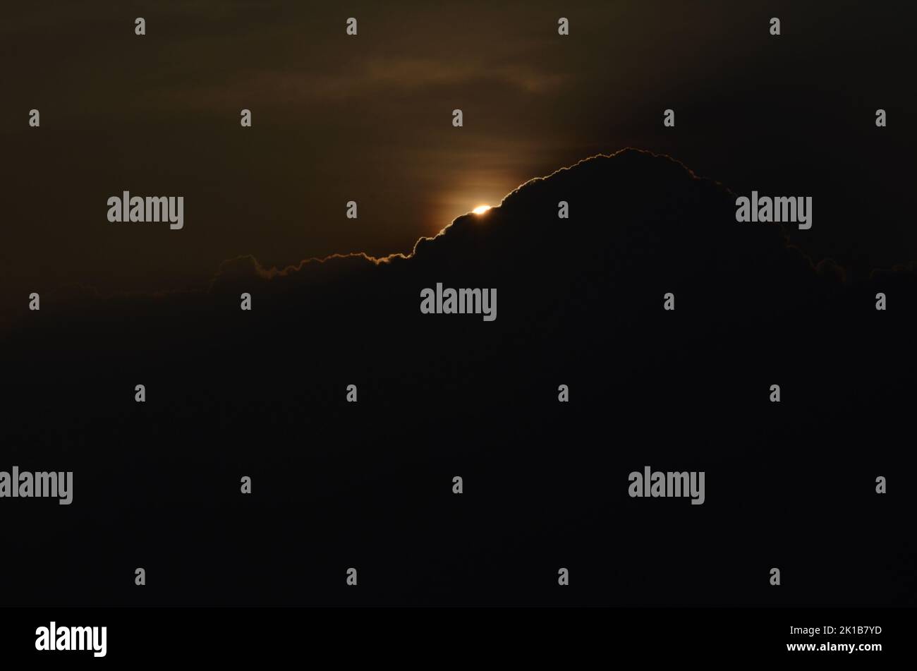 A scenic view of sun beaming through clouds' silhouettes Stock Photo ...