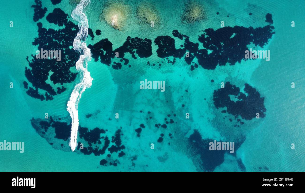 A bird's eye view shot of a boat over a tropical coral reef in a clear ...