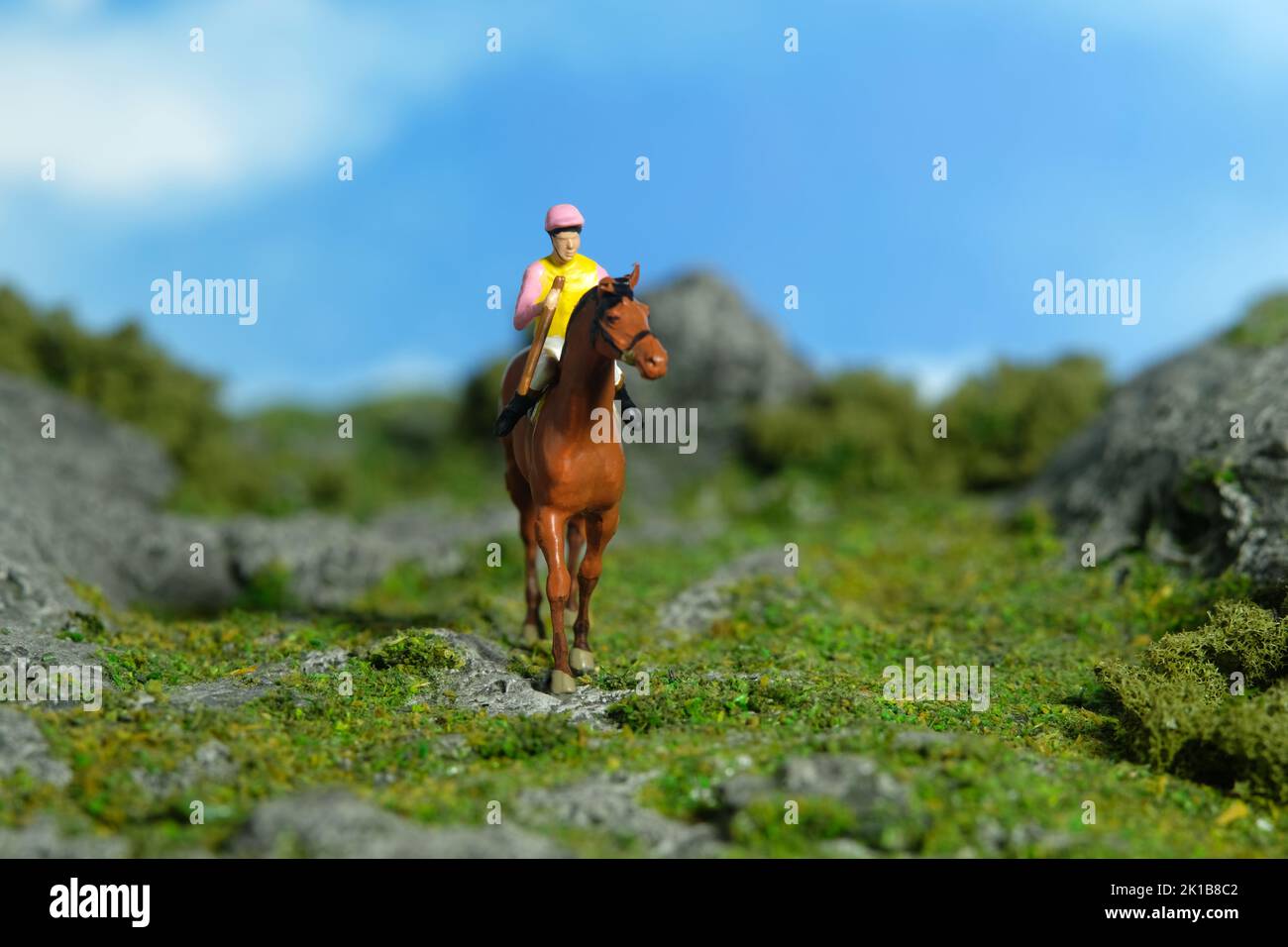 Miniature people toy figure photography. A jockey man riding horse at ...