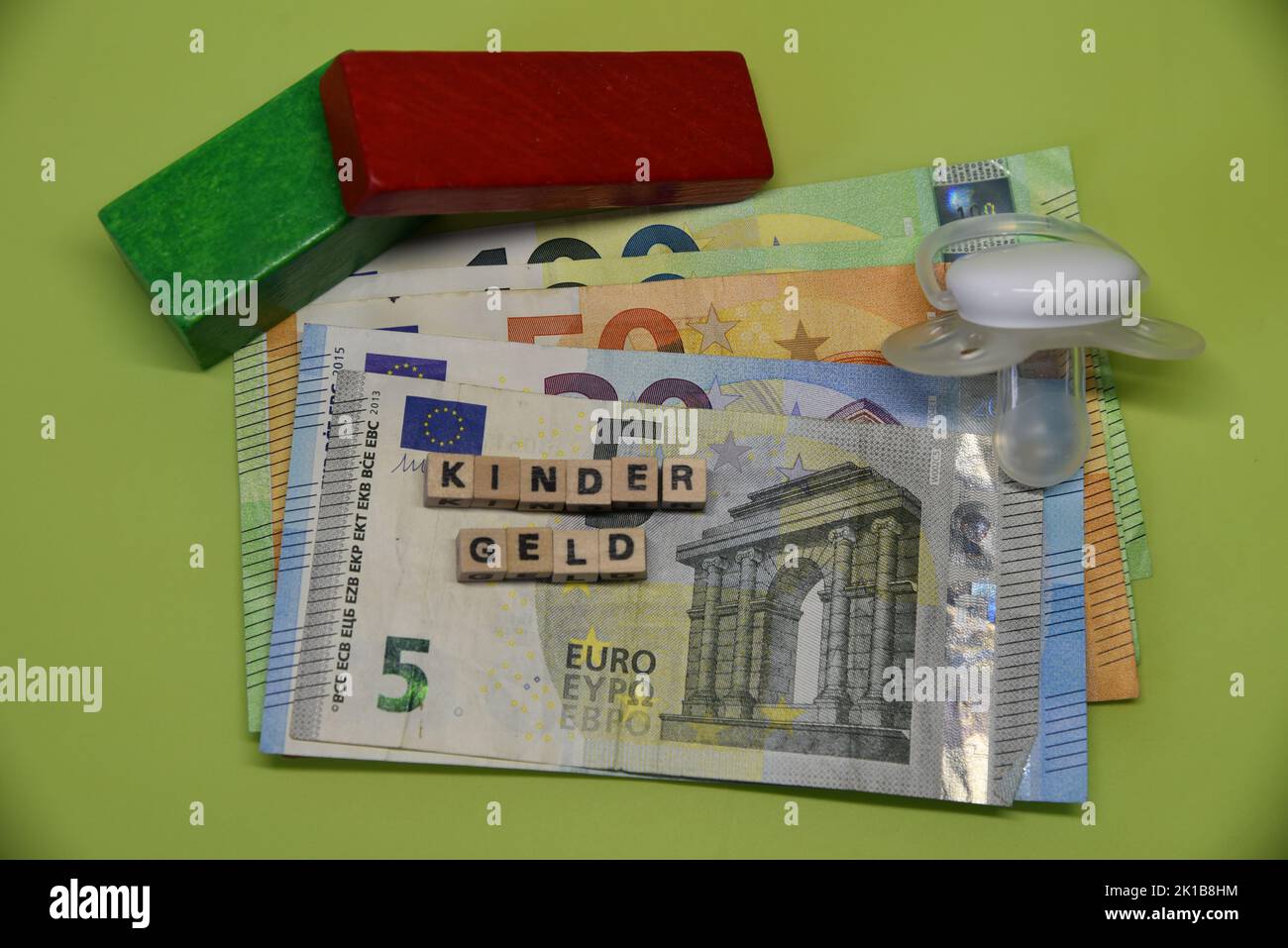 the word child benefit with wodden bricks, a pacifier and euro bank ...