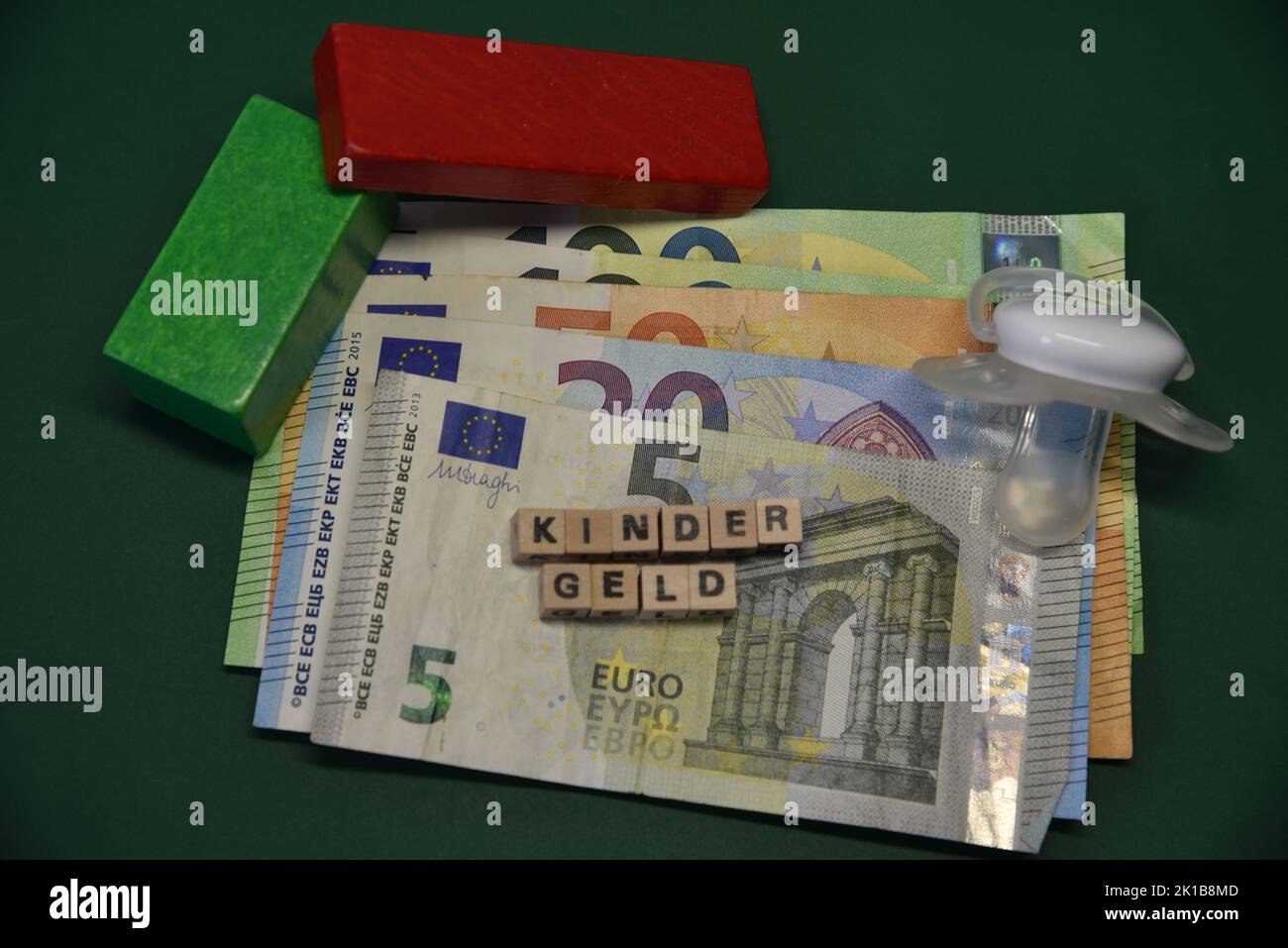 the word child benefit with wodden bricks, a pacifier and euro bank ...