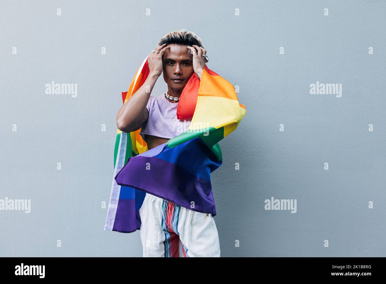 Young stylish guy adjusting his hair while standing outdoors with ...
