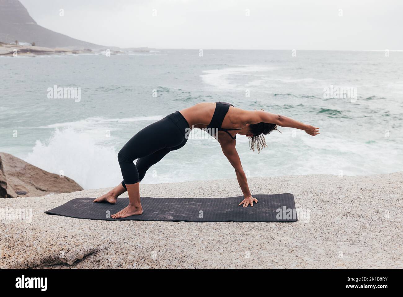 Slim female practicing yoga pose by ocean at coast Stock Photo - Alamy
