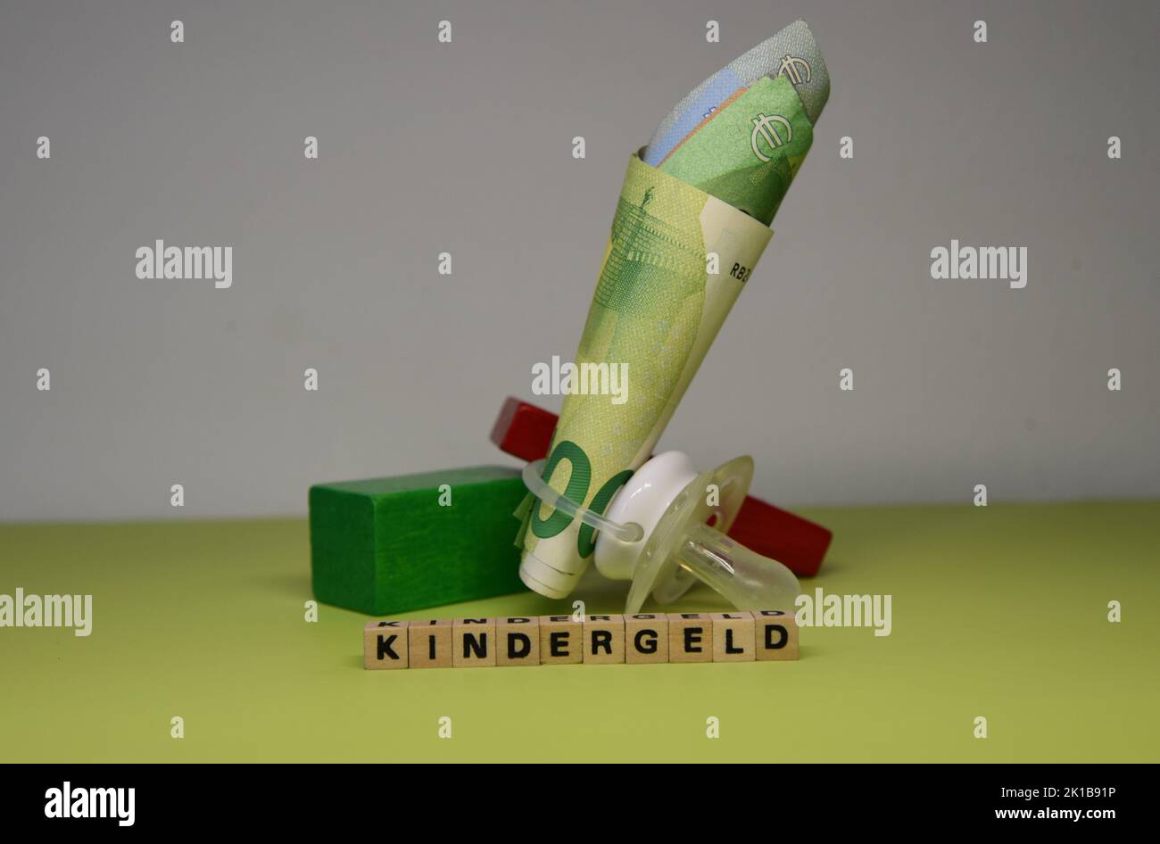 the word child benefit with wodden bricks, a pacifier and euro bank ...