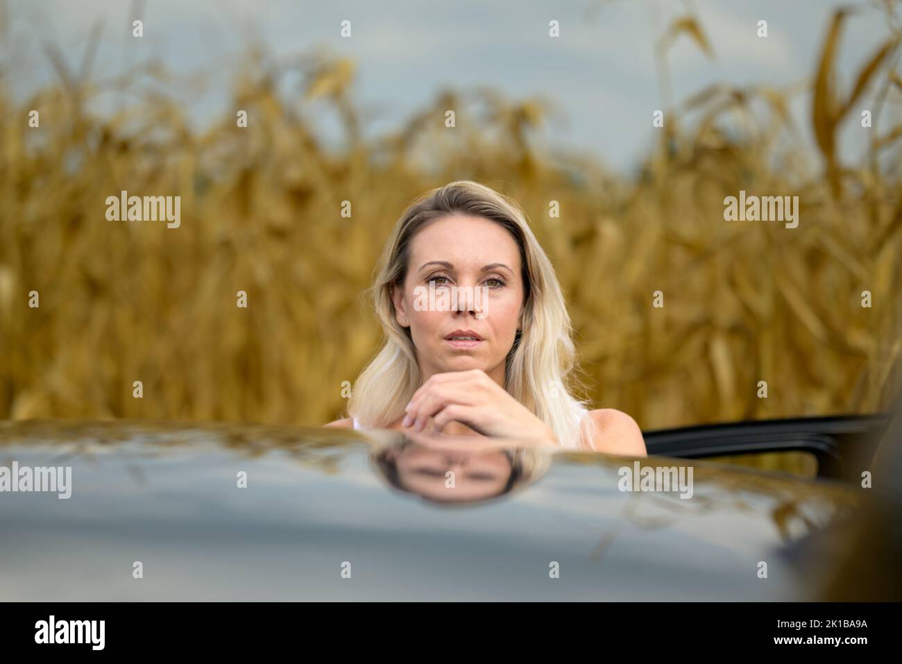 Woman standing by a car with a thoughtful look in the background a ...