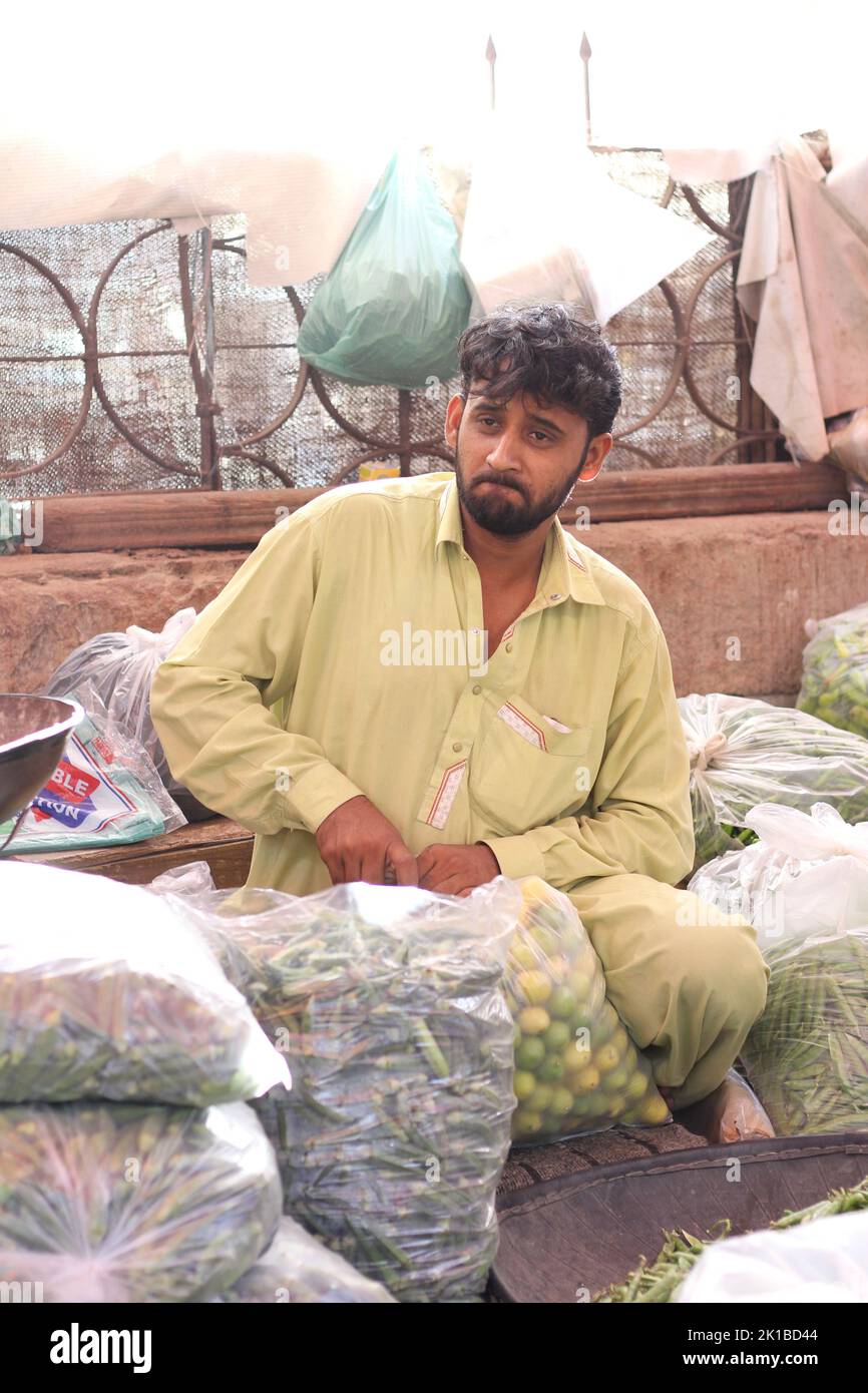 A vertical shot of a Pakistani male with a beard in a market selling ...