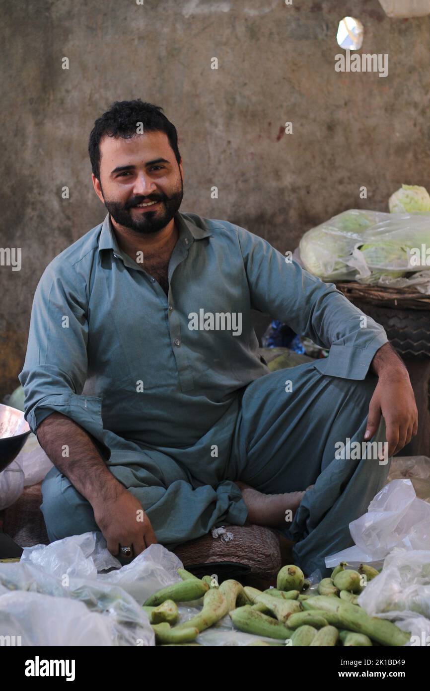 A vertical shot of a Pakistani male with a beard in a market selling ...