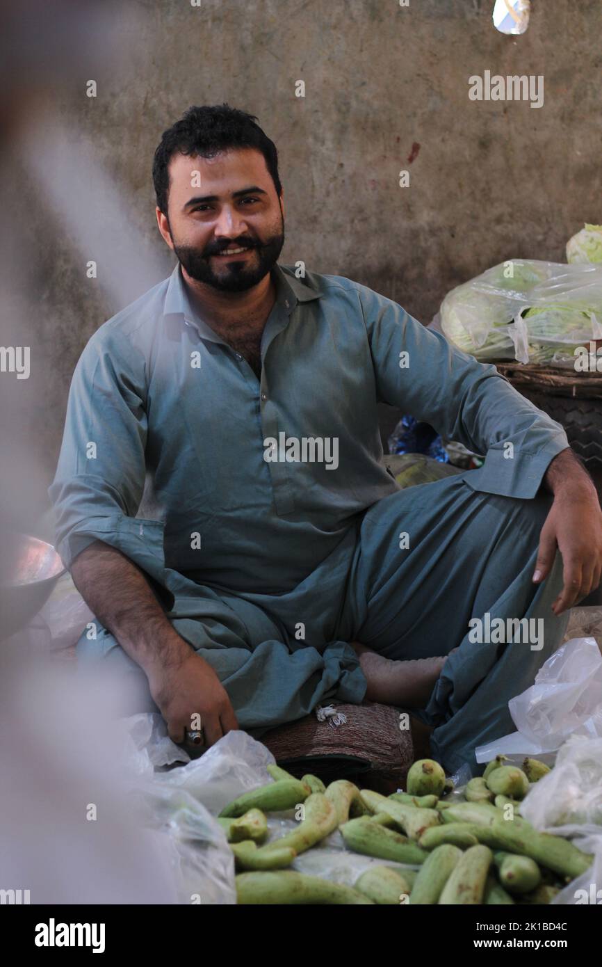 A vertical shot of a Pakistani male with a beard in a market selling ...