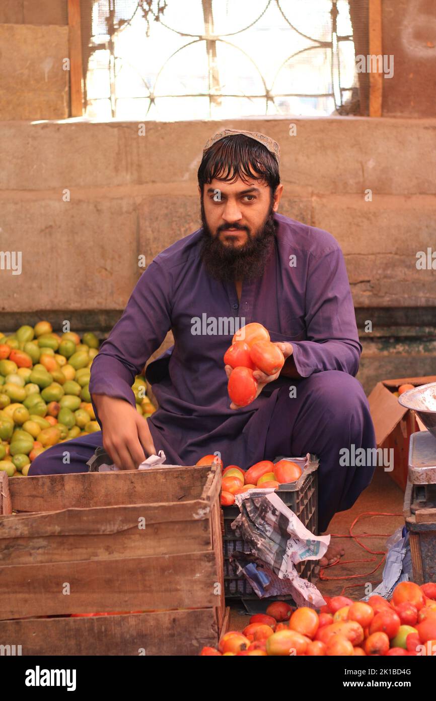 A vertical shot of a Pakistani male with a beard selling fruits in a ...