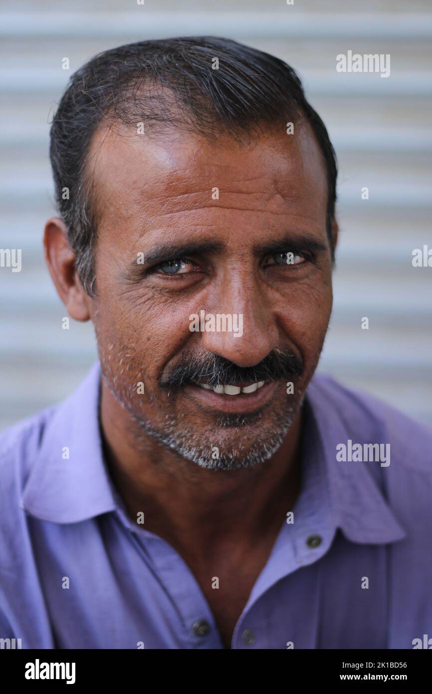 A portrait of a Pakistani middle-aged male with a mustache smiling ...