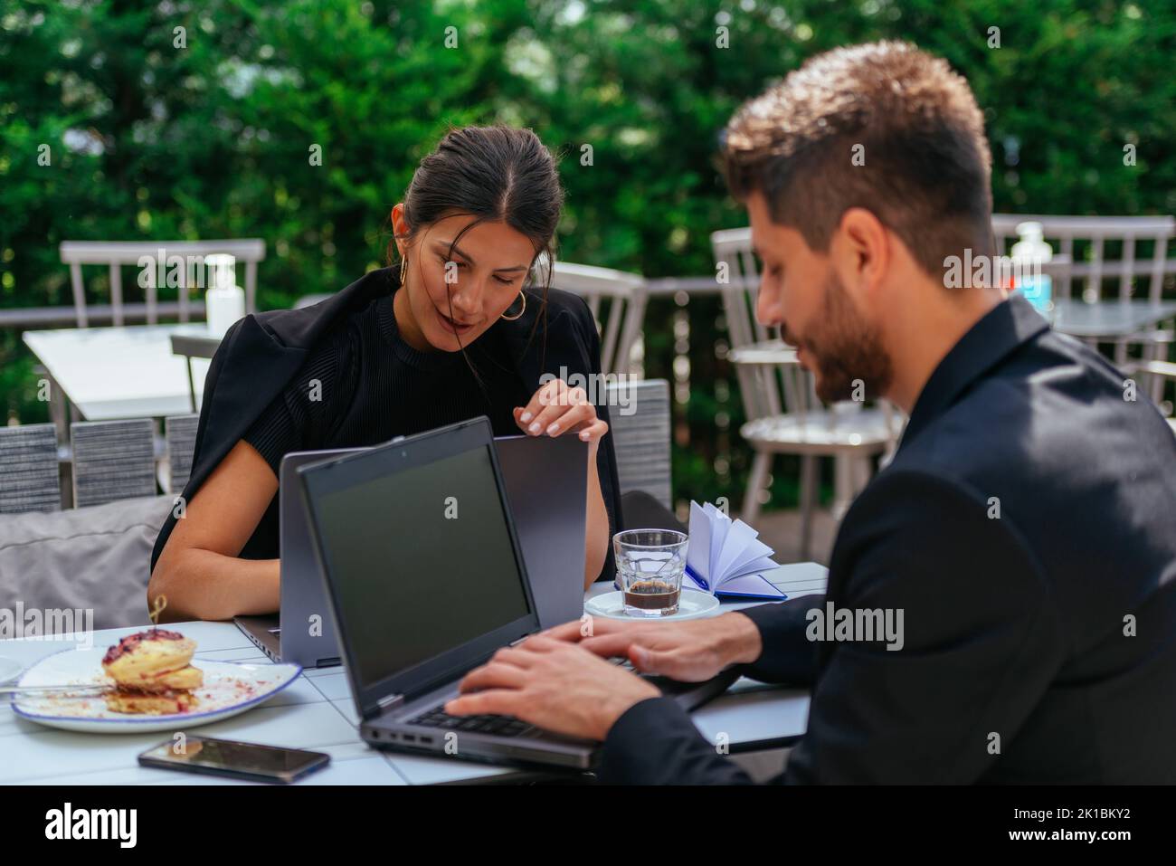 Two business partners are working together on their lap tops, in a ...