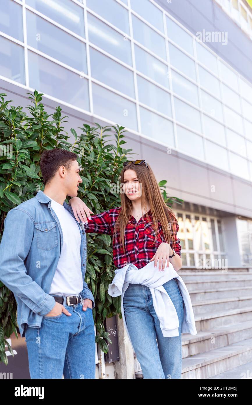 Cute couple having a conversation standng near the bush Stock Photo - Alamy