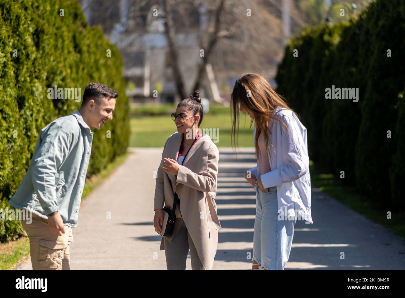 Happy group of three friends laughing and talking in the street Stock ...