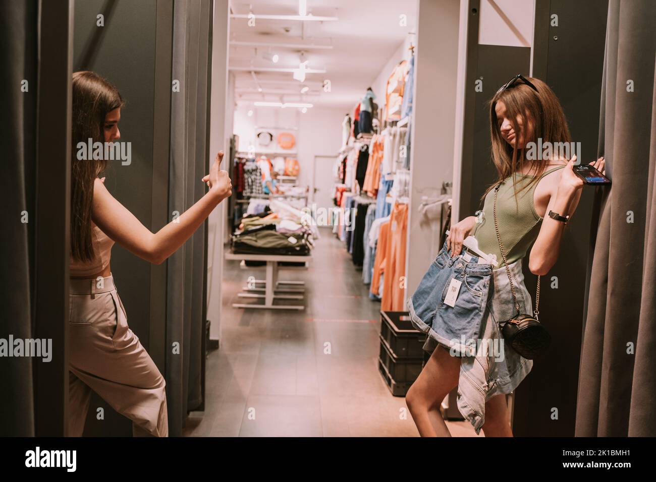 Two teenage girls standing in the changeing room. One of them showing ...