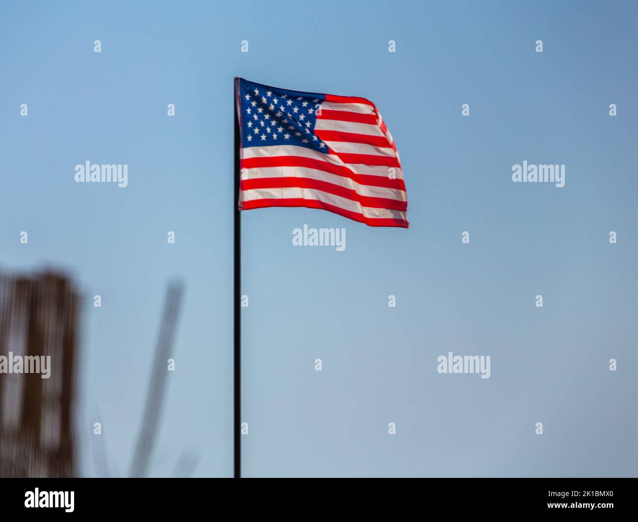The national flag of The United States of America waving in a blue sky ...