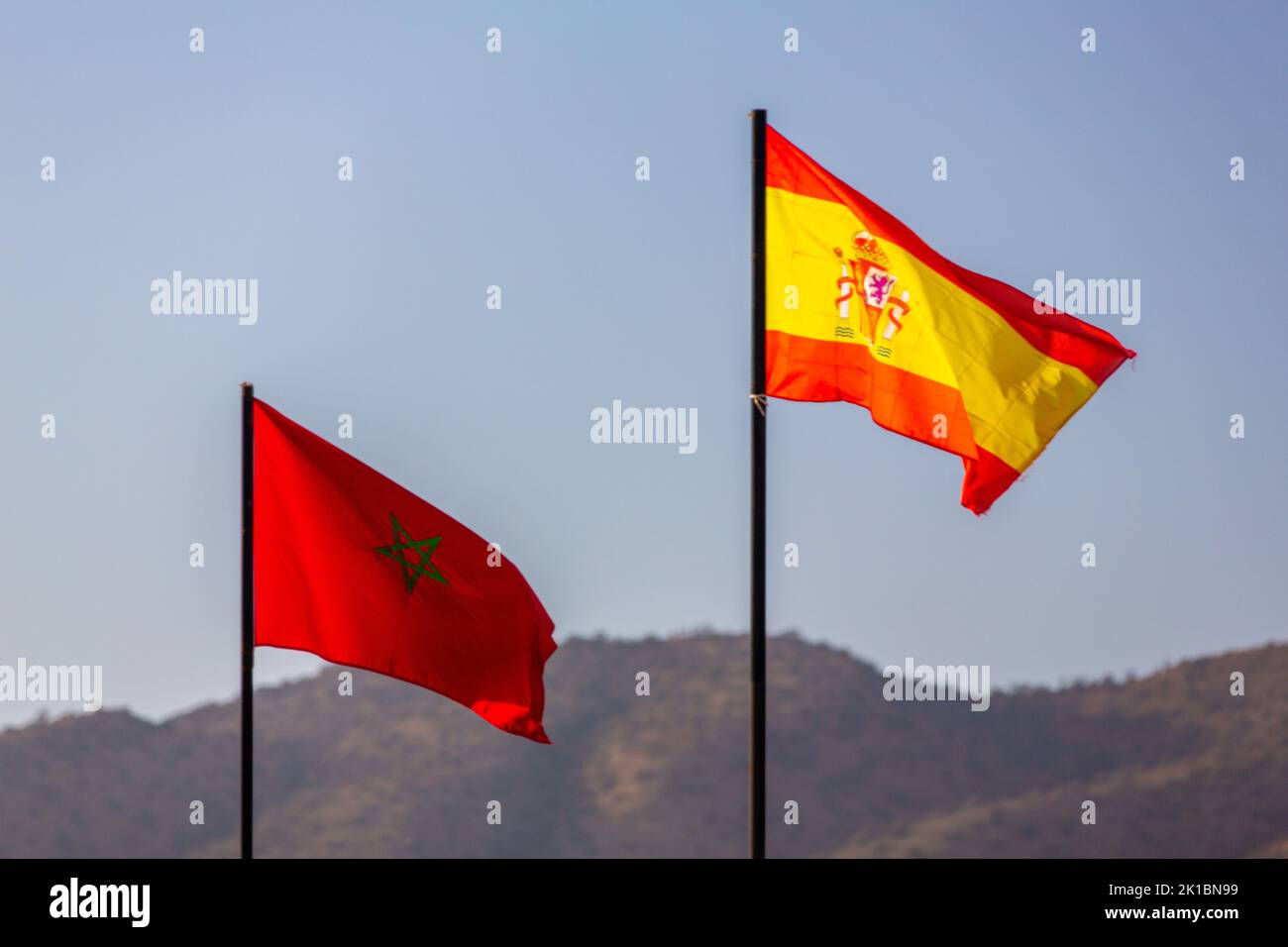 The national flag of morocco and spain waving in a blue sky Stock Photo ...
