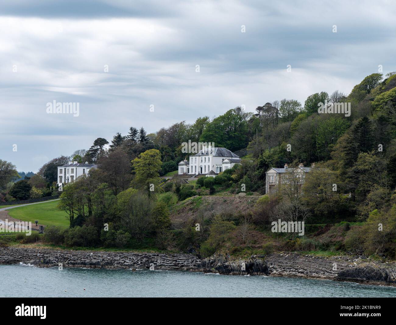 A hill on the shore of the bay. Several buildings and trees on the hill ...
