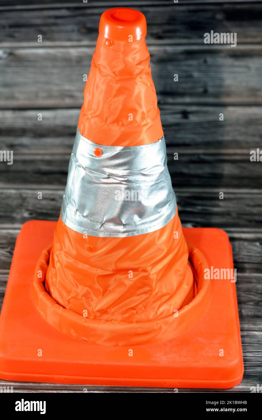 A foldaway car traffic cone isolated on wooden background used as ...