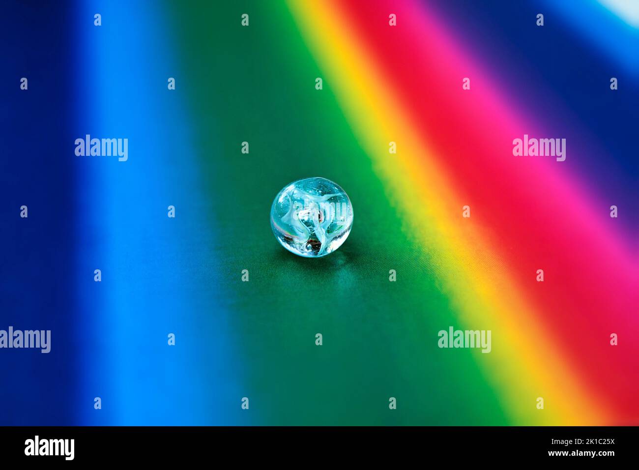 Glass marble, glass ball on rainbow colours Stock Photo - Alamy