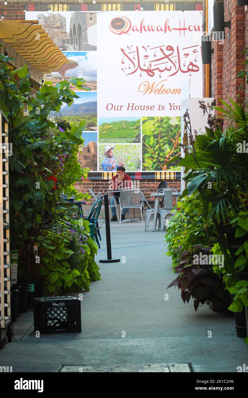 A vertical shot of a man sitting in an outdoor cafe with a poster ...