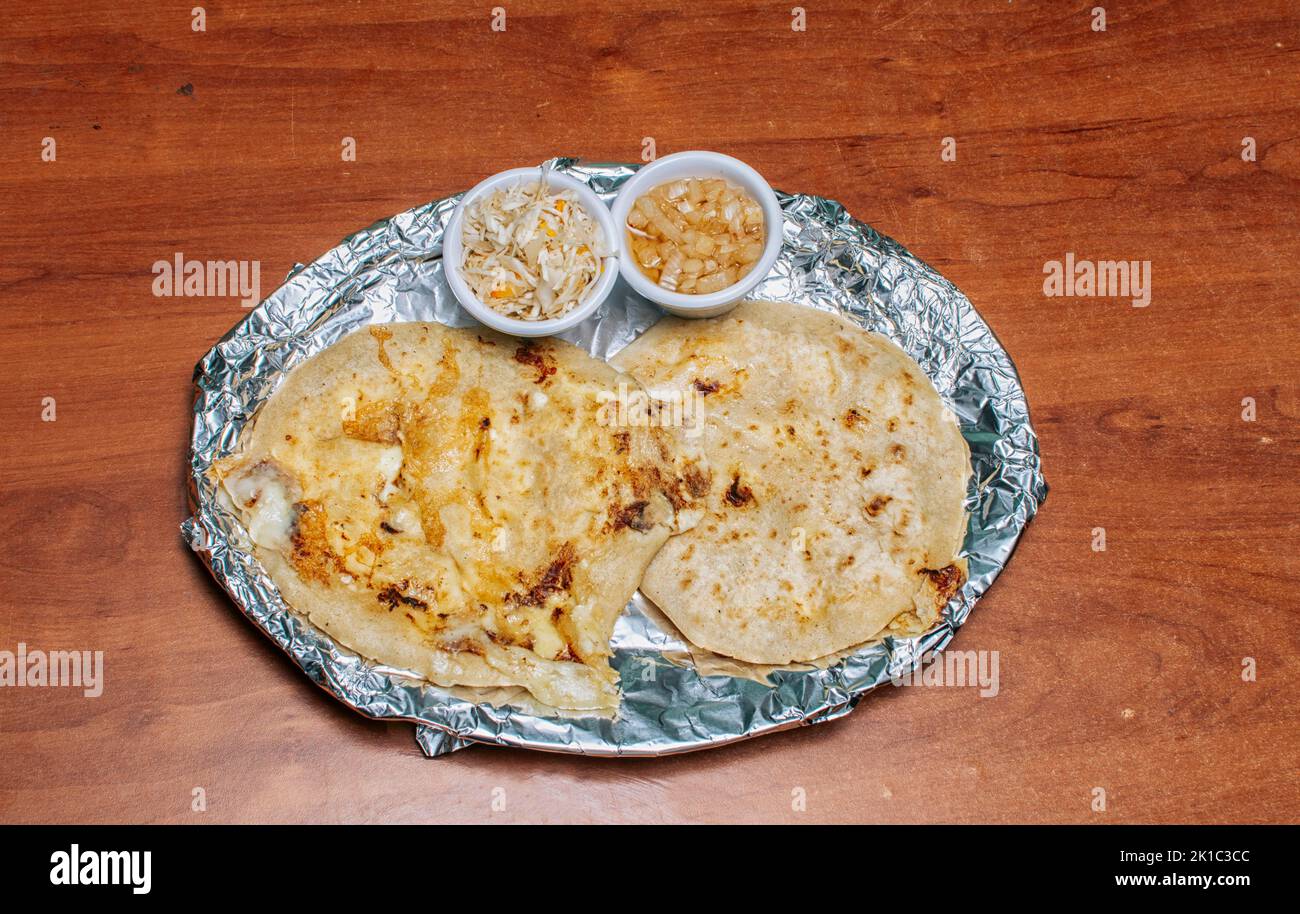 Two Nicaraguan pupusas served with salad on the table. Delicious ...