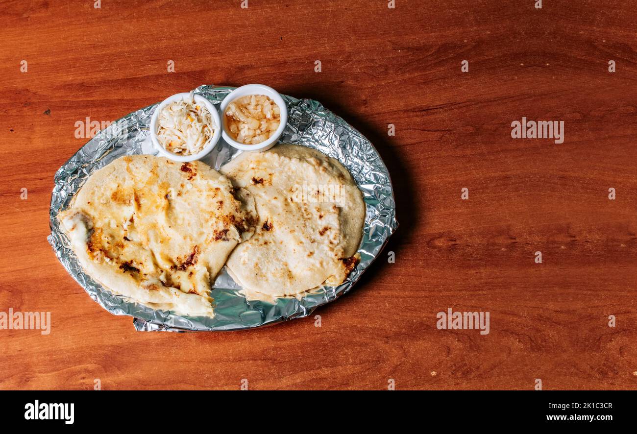 Traditional pupusas served with salad on the table. Top view of two ...