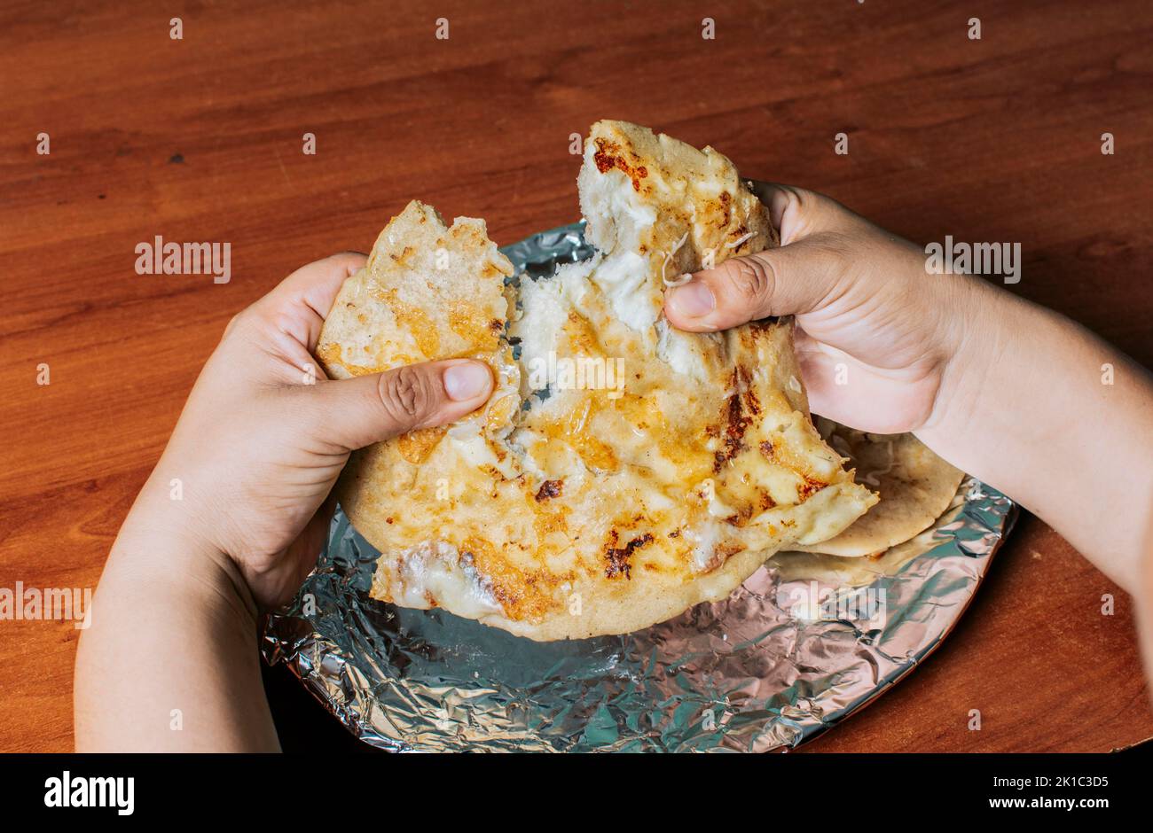 Hands dividing delicious Nicaraguan pupusa on the table, View of hands ...