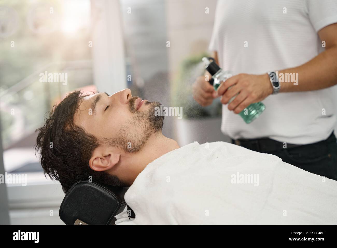 Chill brunette guy laying down in barbershop chair Stock Photo - Alamy