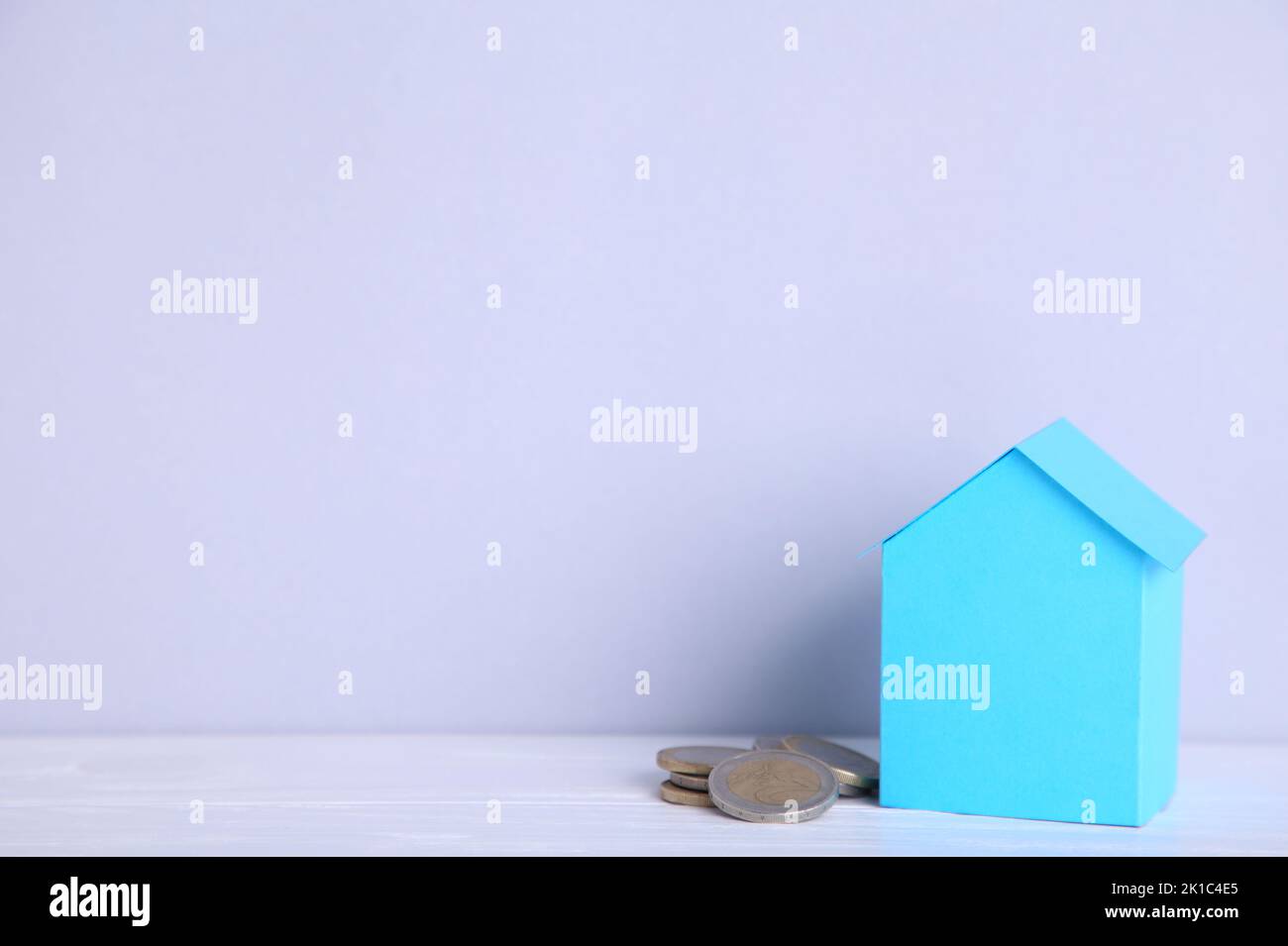 Blue paper house with coins on a grey background Stock Photo - Alamy