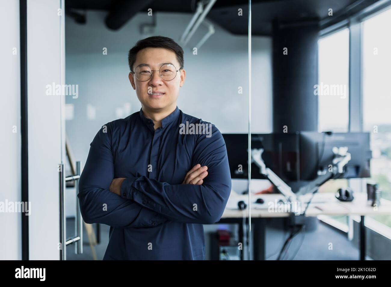 Portrait of successful Asian programmer, team leader company owner smiling and looking at camera ...