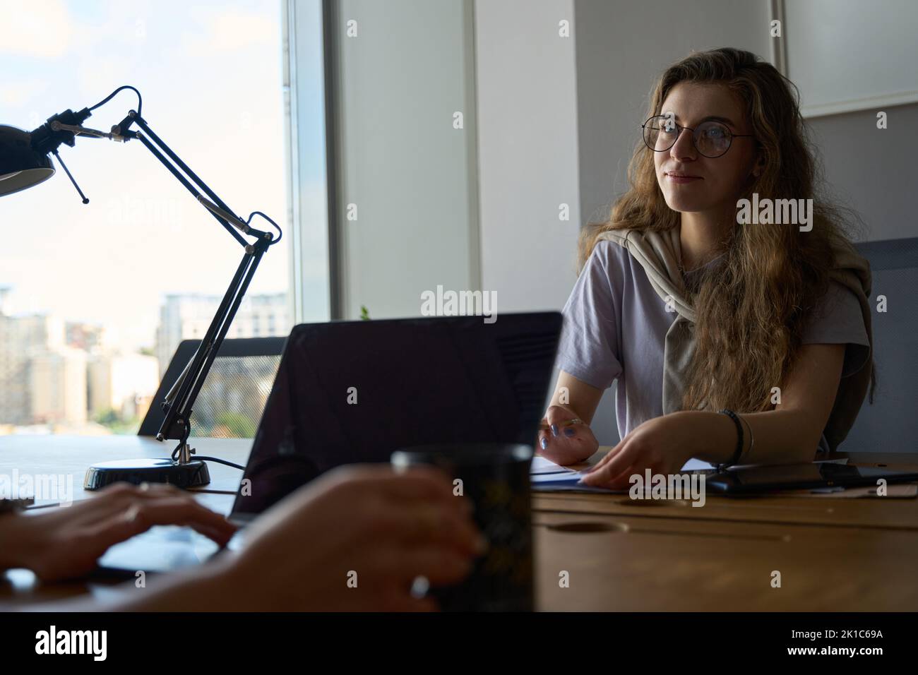Lady sits at desk and looks at the person opposite Stock Photo - Alamy