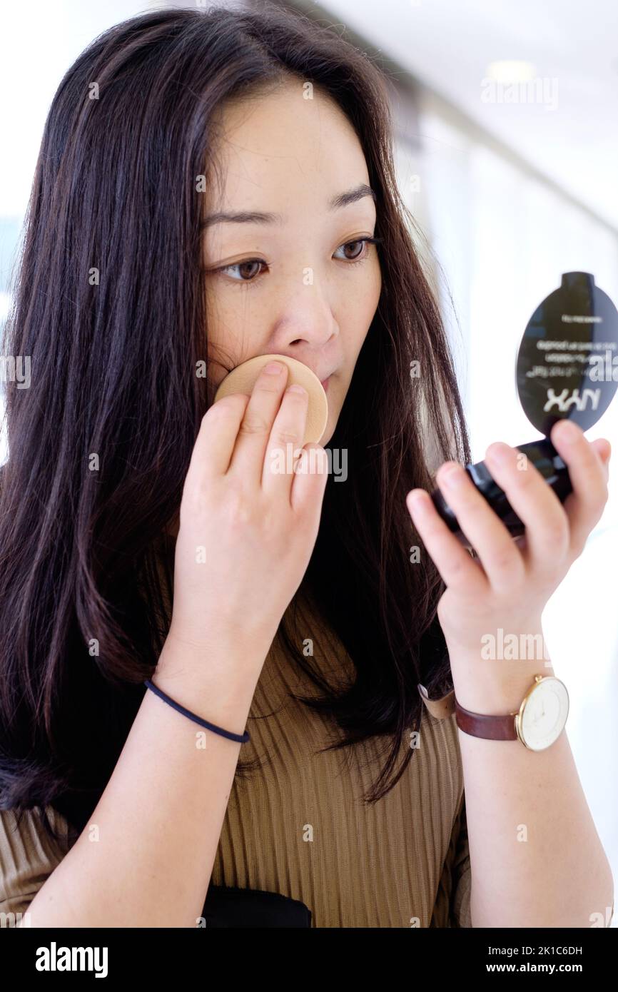 Asian lady puts on face powder Stock Photo - Alamy