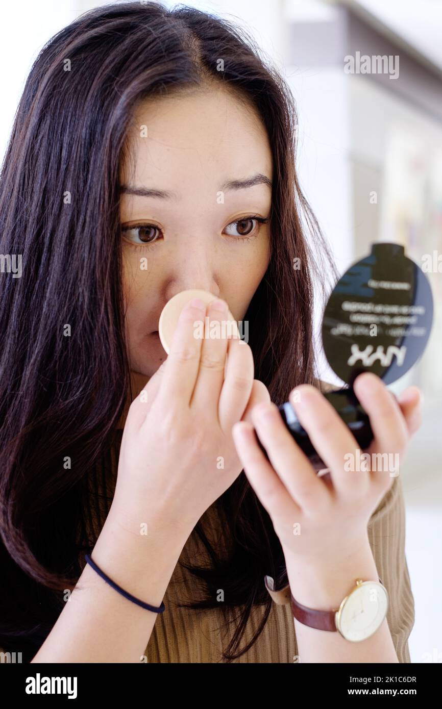 Asian lady puts on face powder Stock Photo - Alamy