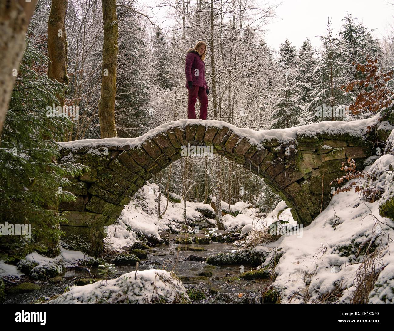 Woman in red standing on icy bridge in winter landscape, Black Forest ...