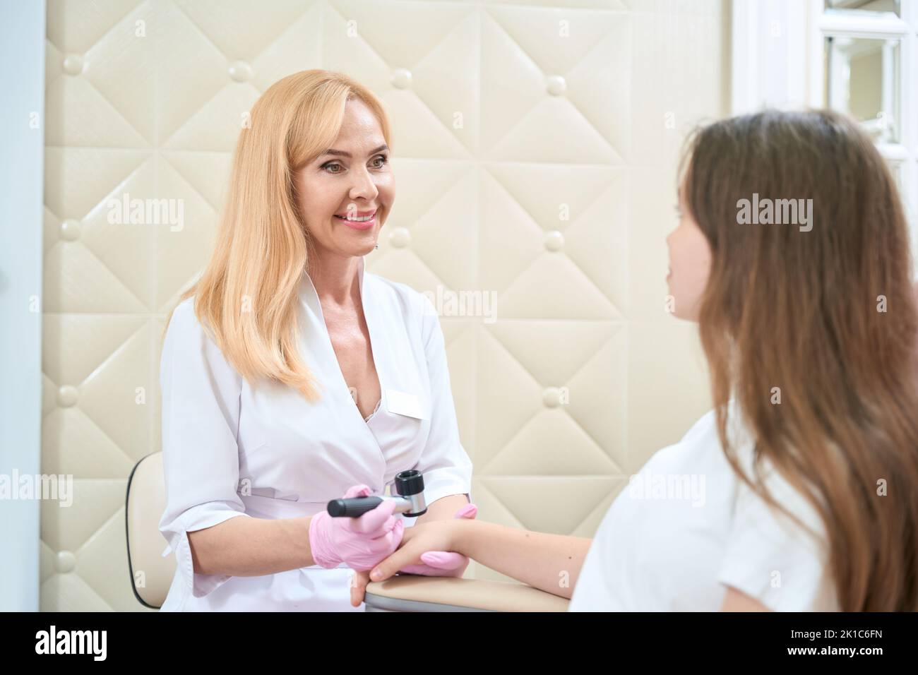 Woman doctor cosmetologist checks neoplasms with dermatoscope on ...