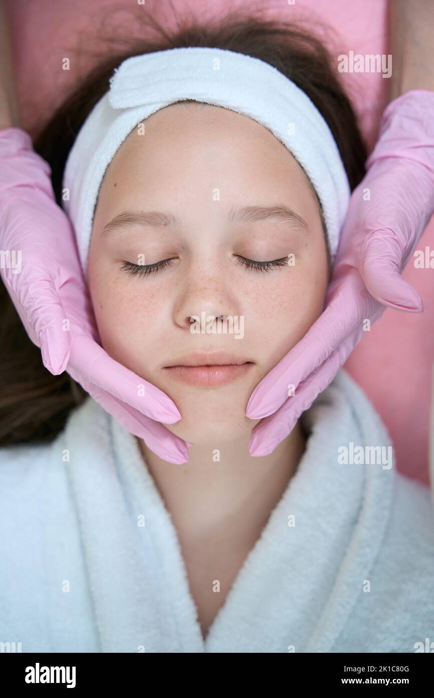 Women hands hold face of girl lying in chair Stock Photo - Alamy