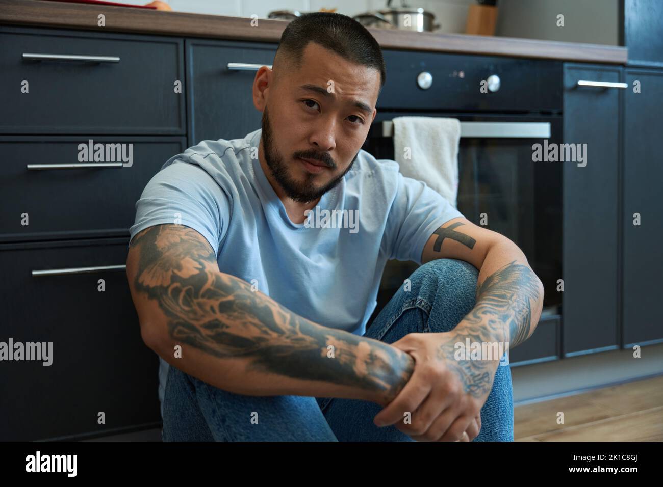 Young asian man sits on floor in kitchen, hugging his knees Stock Photo ...