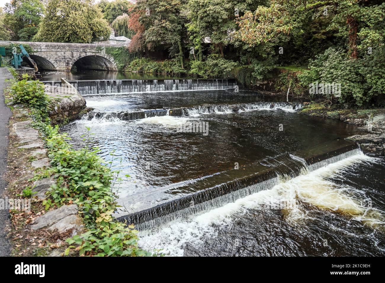 The River Tavy flowing under a bridge and over small dams at Tavistock ...