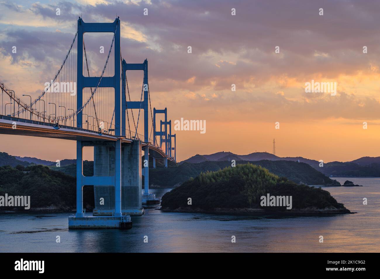 Sunset glow lingers over long suspension bridge between small islands ...