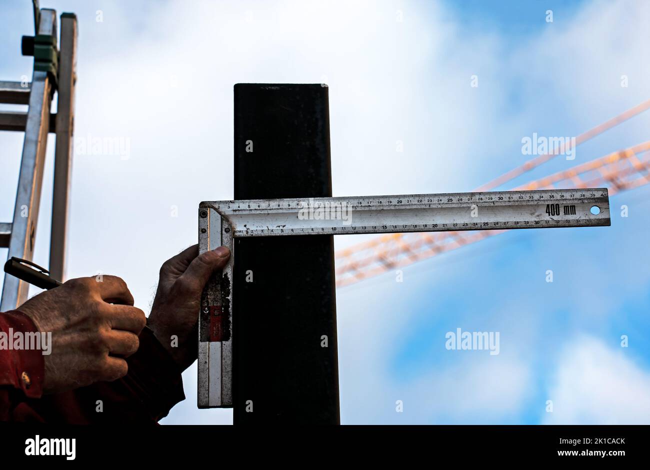 A skilled worker measures and marks a line on a square pipe with an ...