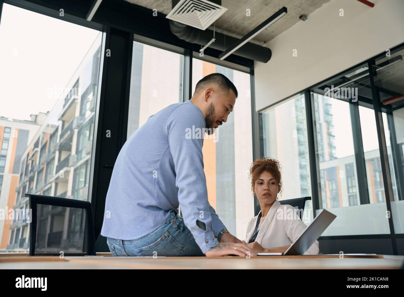 Two office workers sitting at portable computer Stock Photo - Alamy